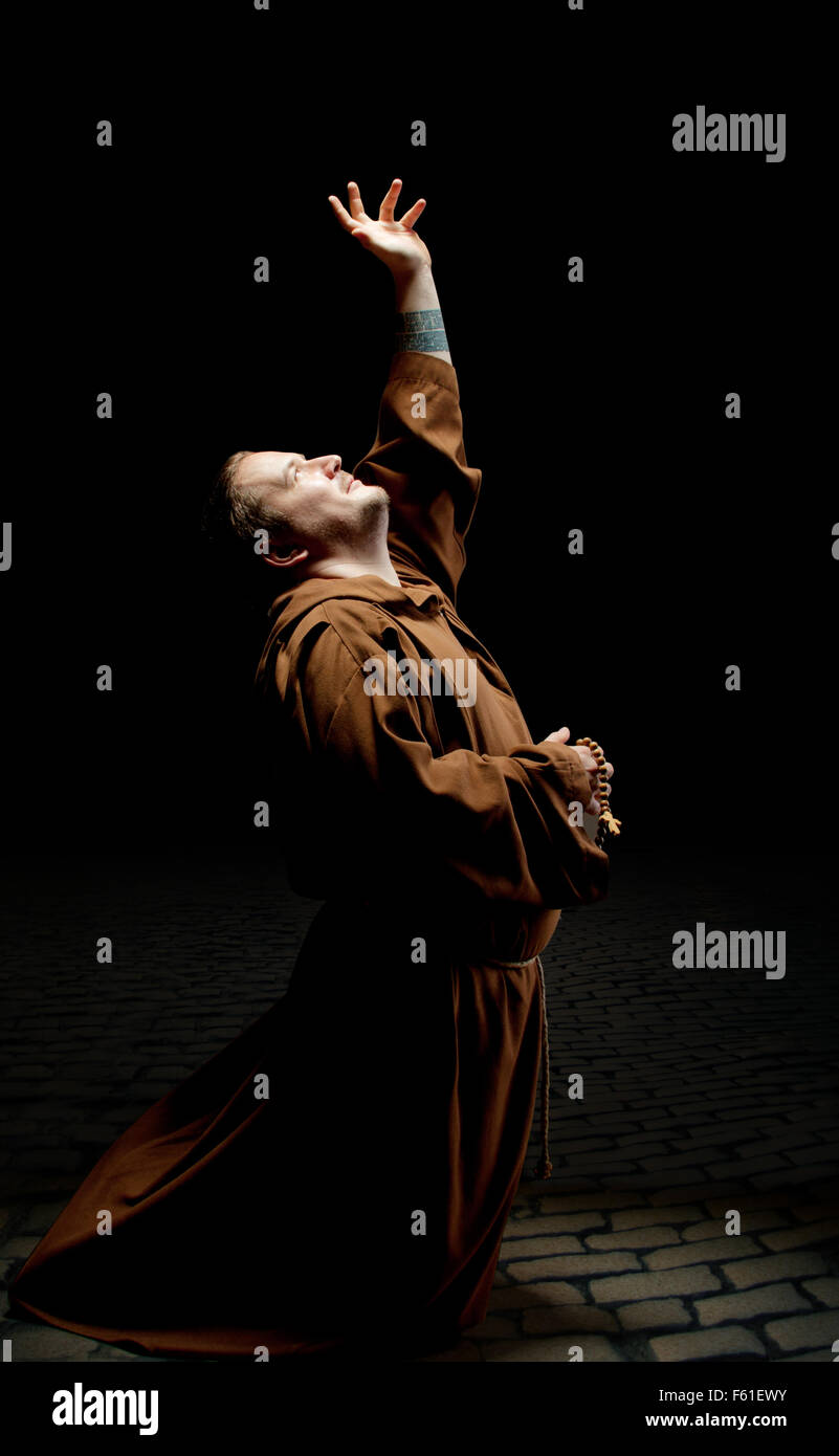 Monk standing on kneels and asking God for help Stock Photo - Alamy