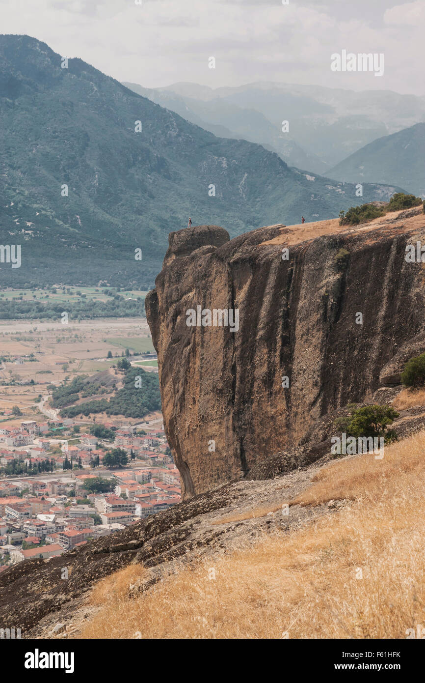 People walking to the edge of a cliff, having the view of a town right ...