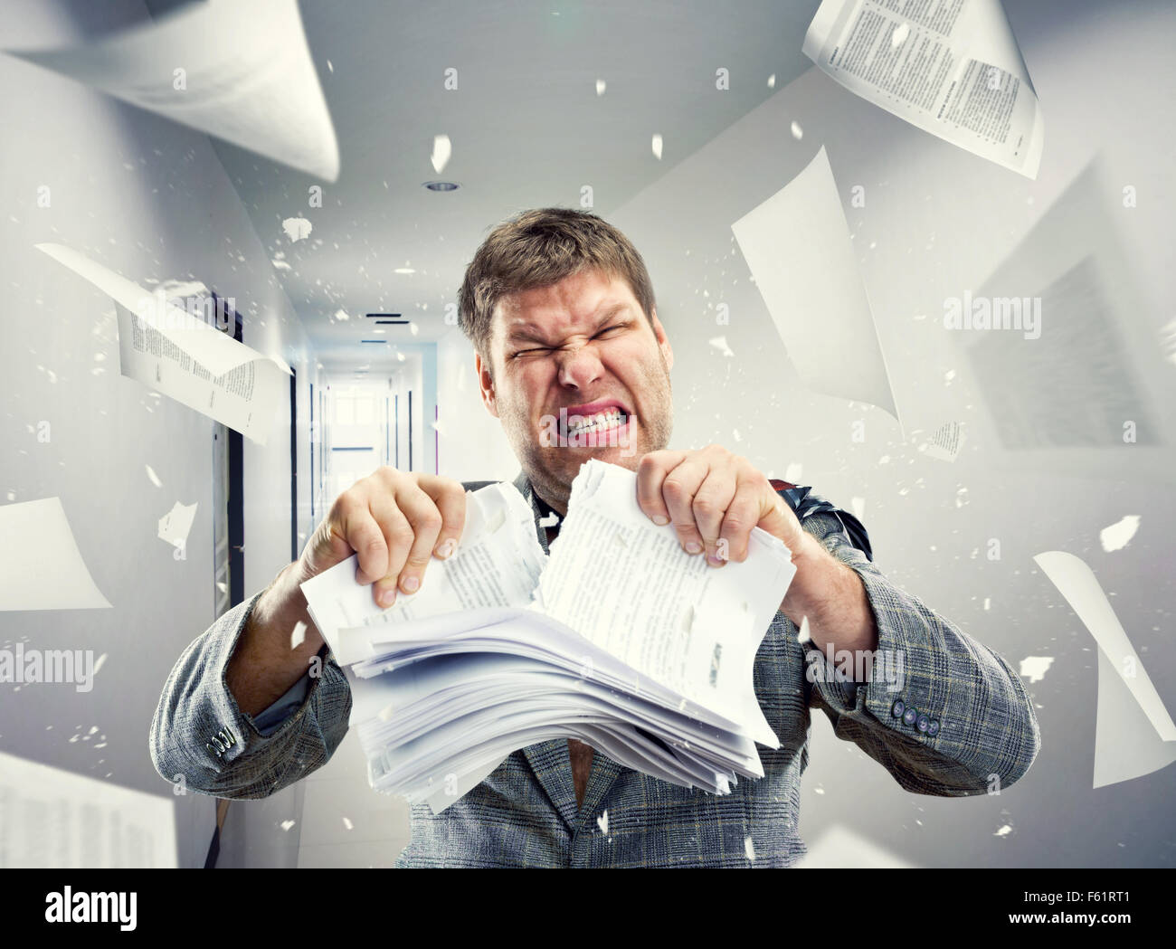 Stressed businessman tearing out stack of paper at office Stock Photo ...