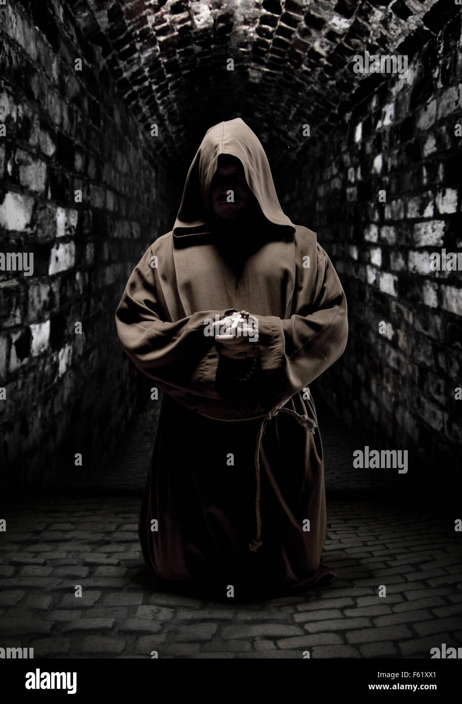 Mystery monk praying on kneels in dark temple corridor Stock Photo - Alamy