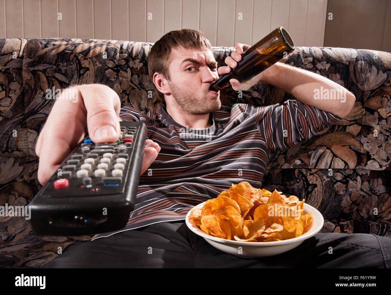 Man with beer and chips watching TV at home Stock Photo - Alamy