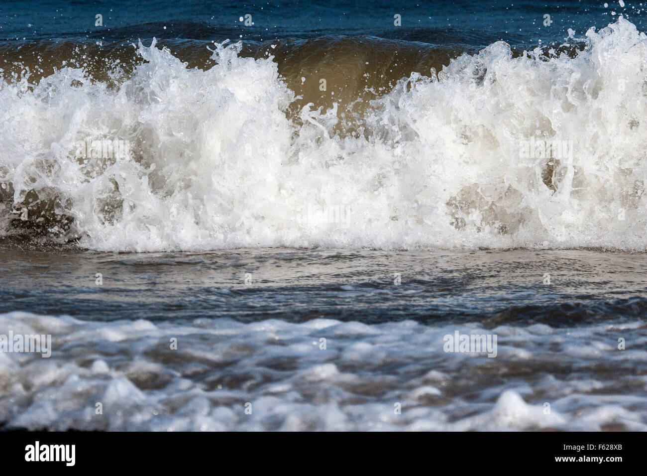 A small wave breaks on to the beach Stock Photo - Alamy