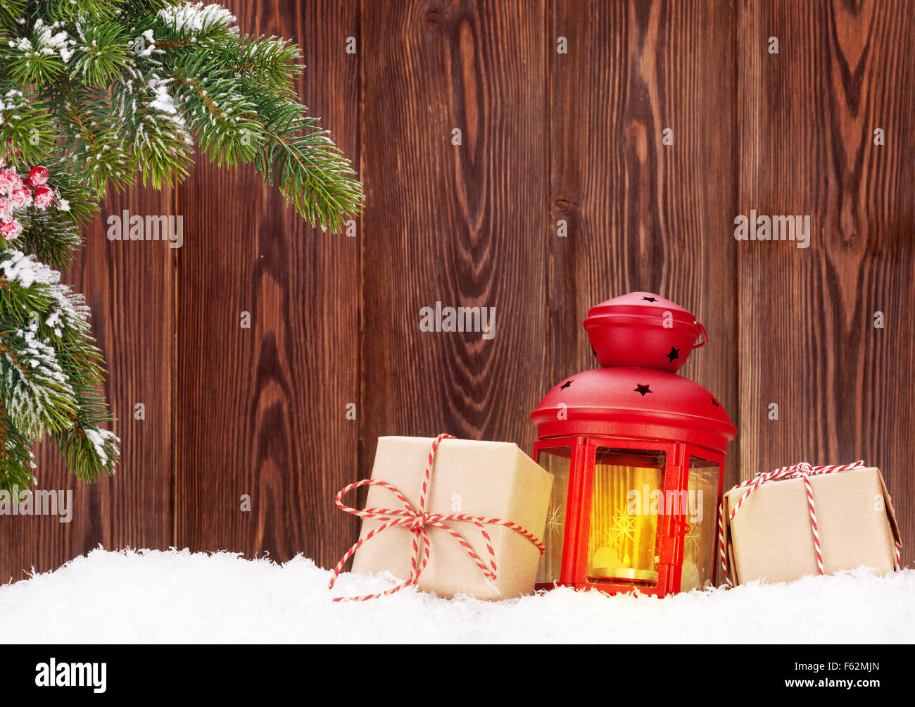 Christmas candle lantern, gift boxes and fir tree in snow Stock Photo ...