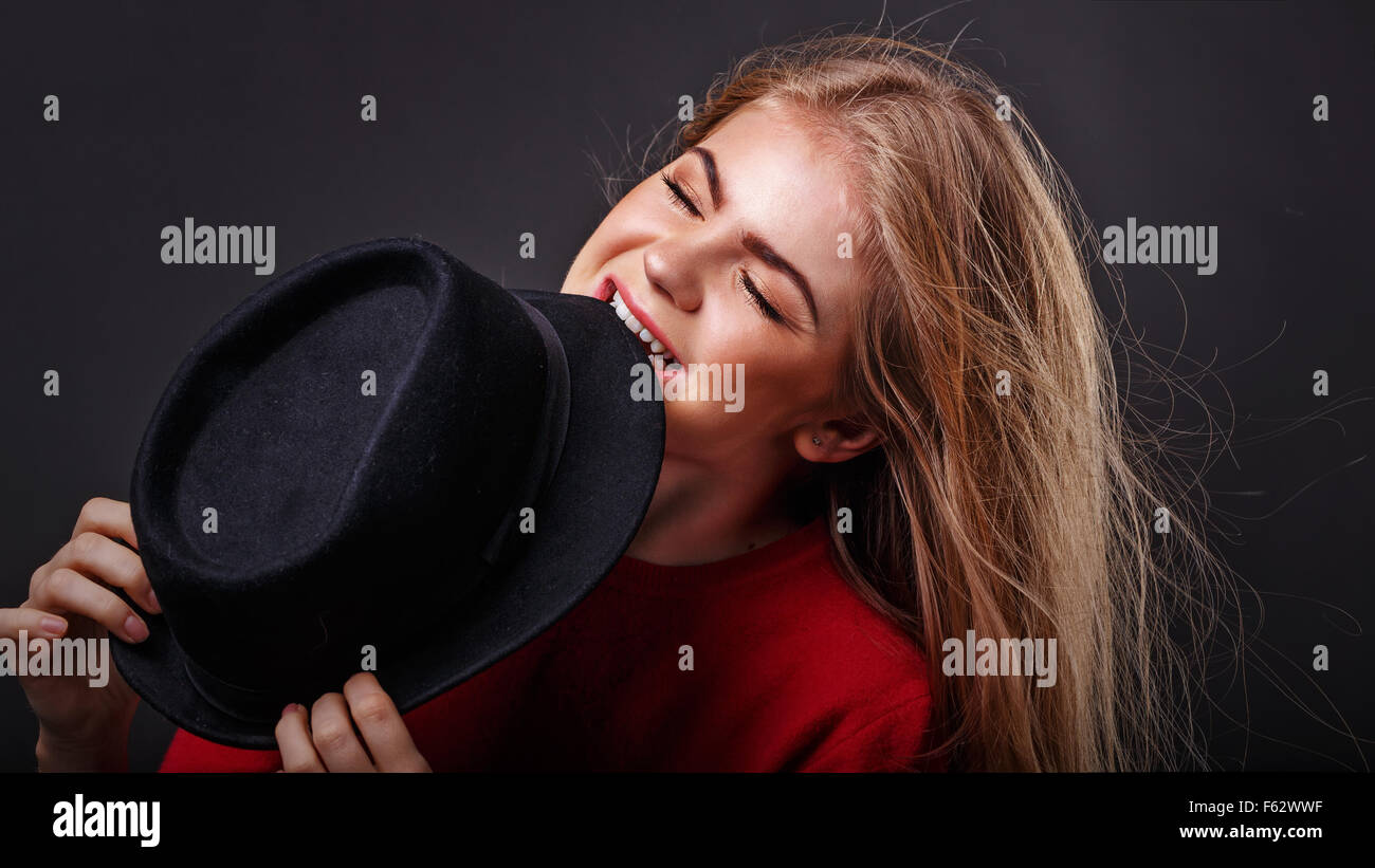 Young attractive woman, eyes closed, biting edge of the hat. Pleasure. Youth fashion Stock Photo ...