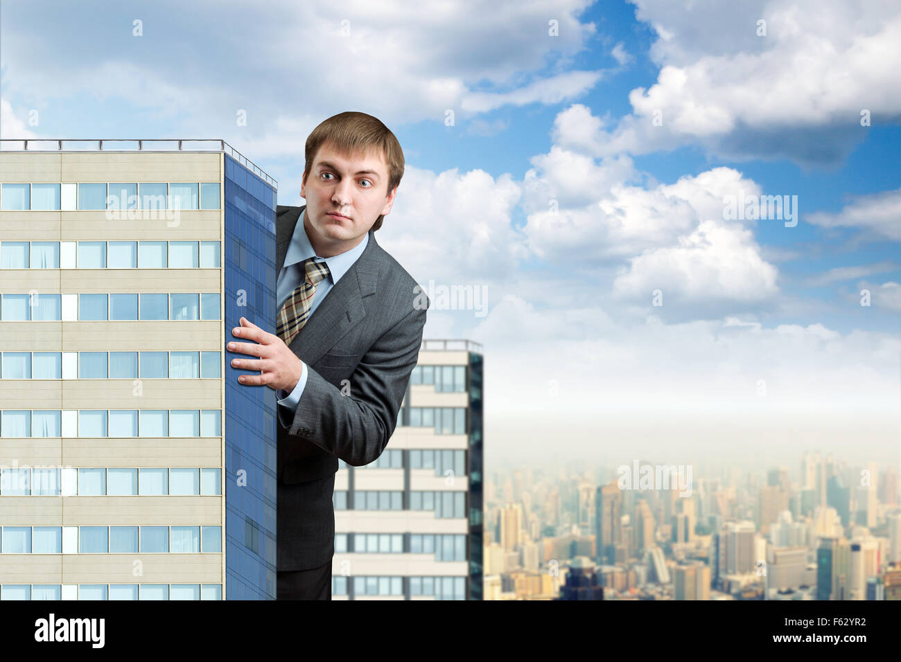 Businessman stands behind the skyscrapers against blue sky Stock Photo ...