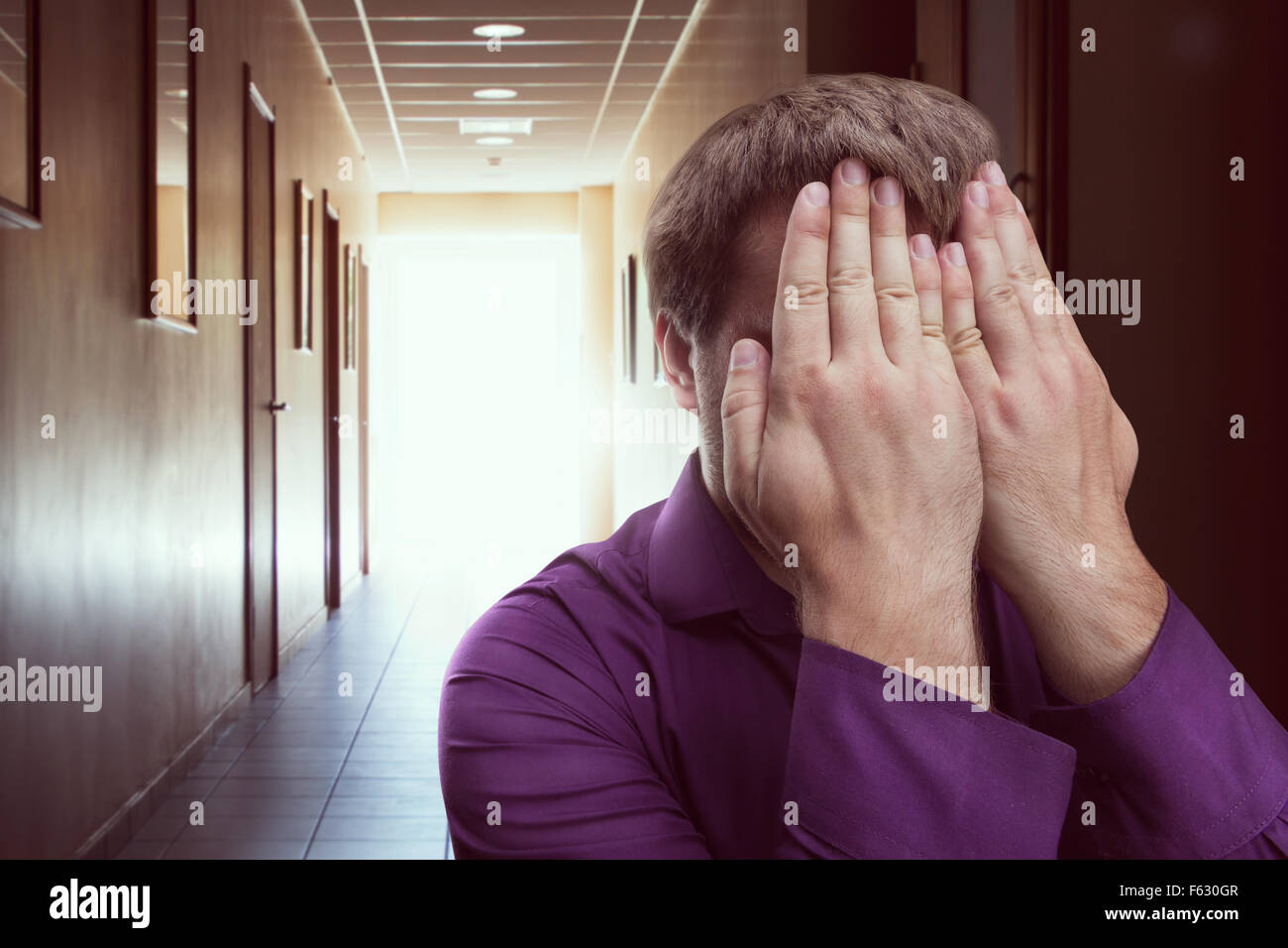 Man covers his face with hands standing in the corridor Stock Photo - Alamy