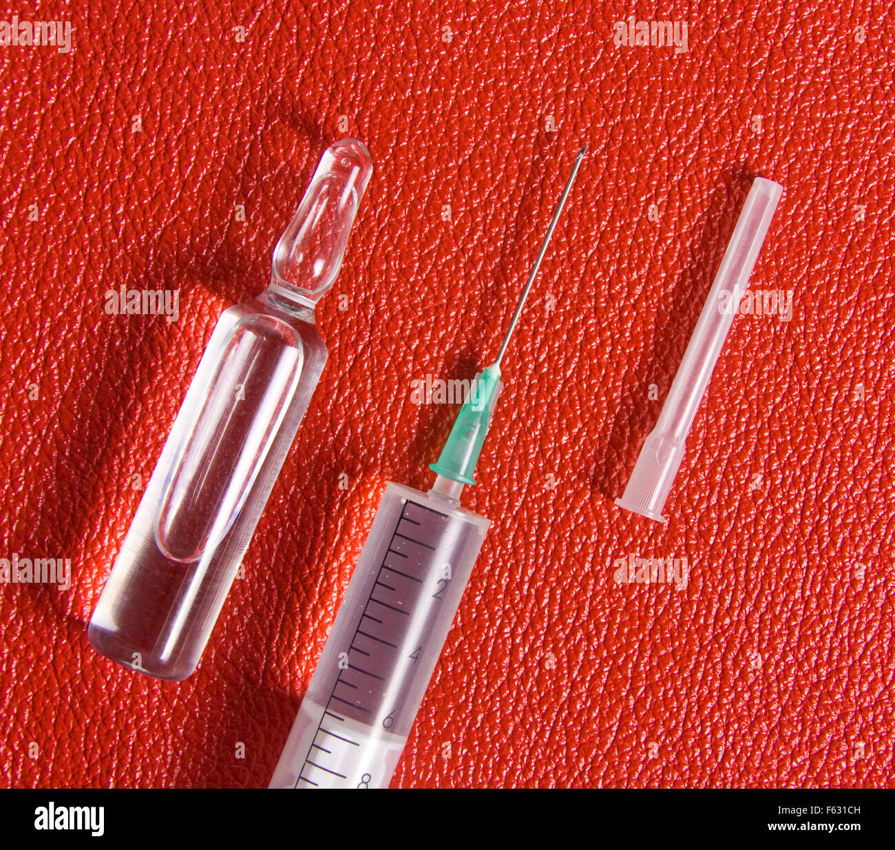 Medicine and open syringe on red surface Stock Photo - Alamy