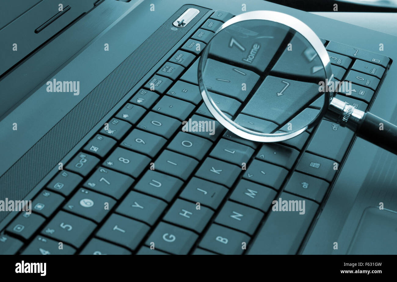 Magnifying glass on laptop computer. Toned in blue Stock Photo - Alamy