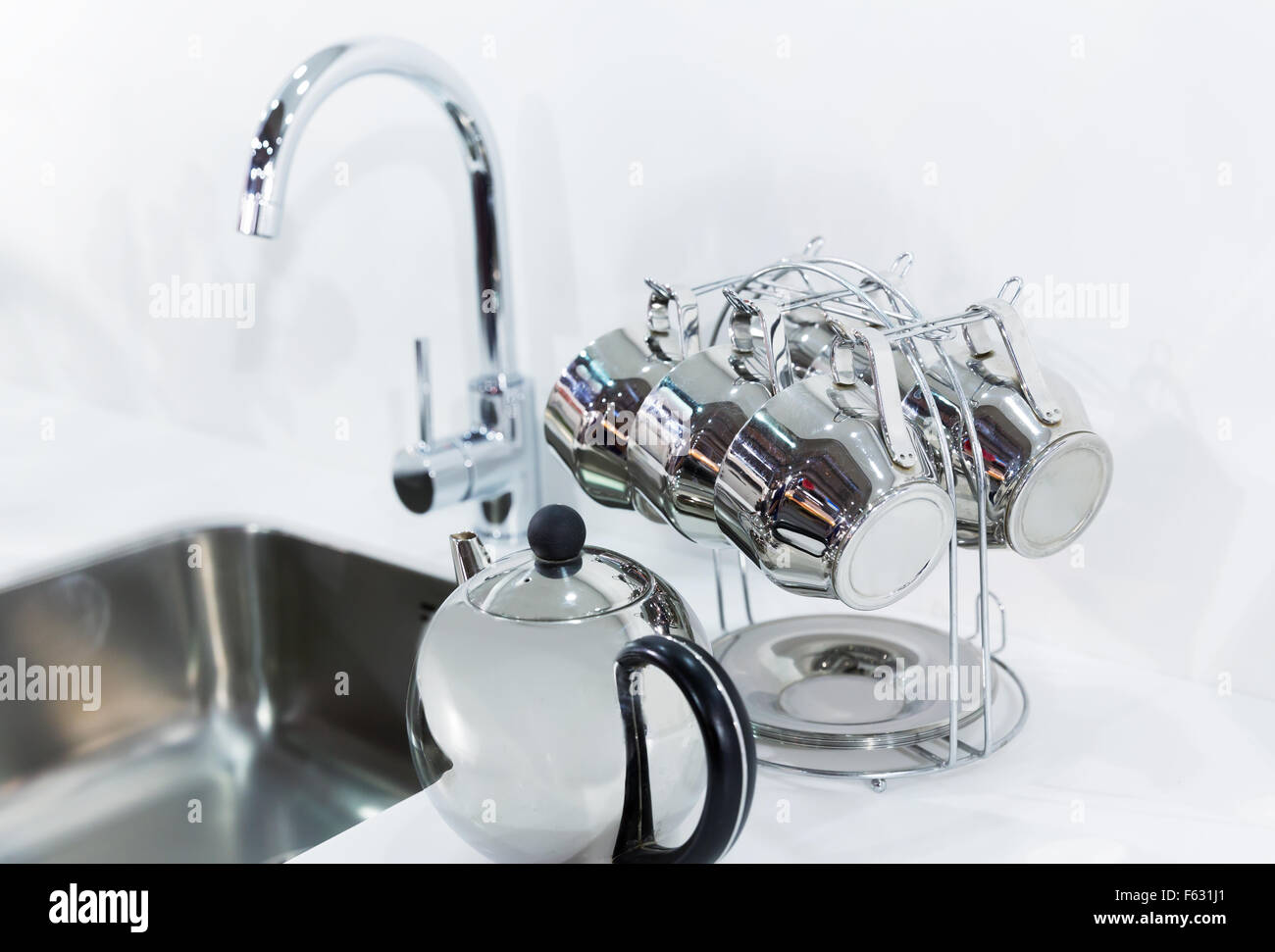 Metal cups drying near metal sink Stock Photo - Alamy