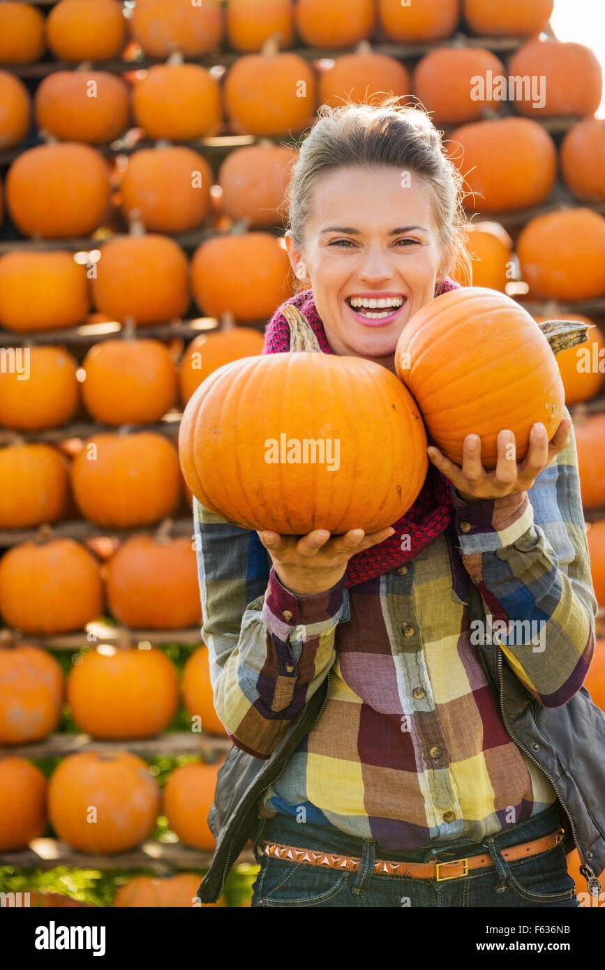 Portrait of young smiling beautiful woman holding pumpkins in front of ...