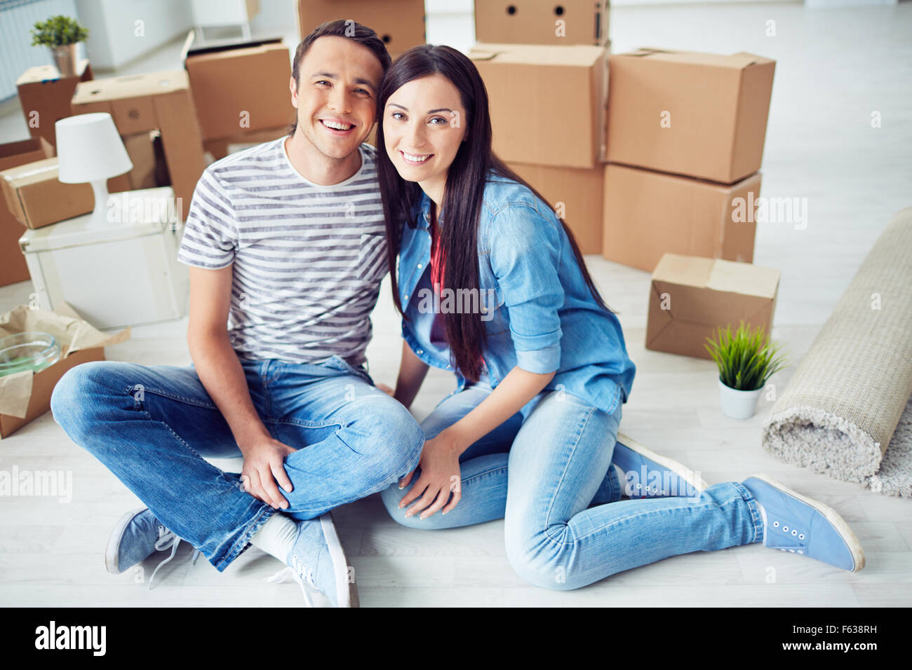 Cheerful couple sitting in empty new house Stock Photo - Alamy