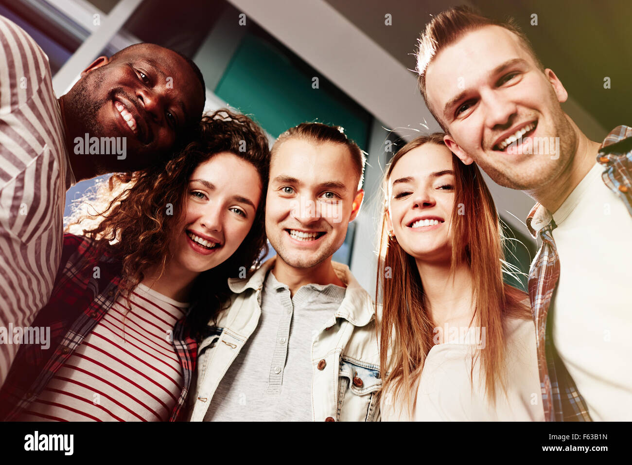 Group of cheerful friends looking at camera with toothy smiles Stock ...