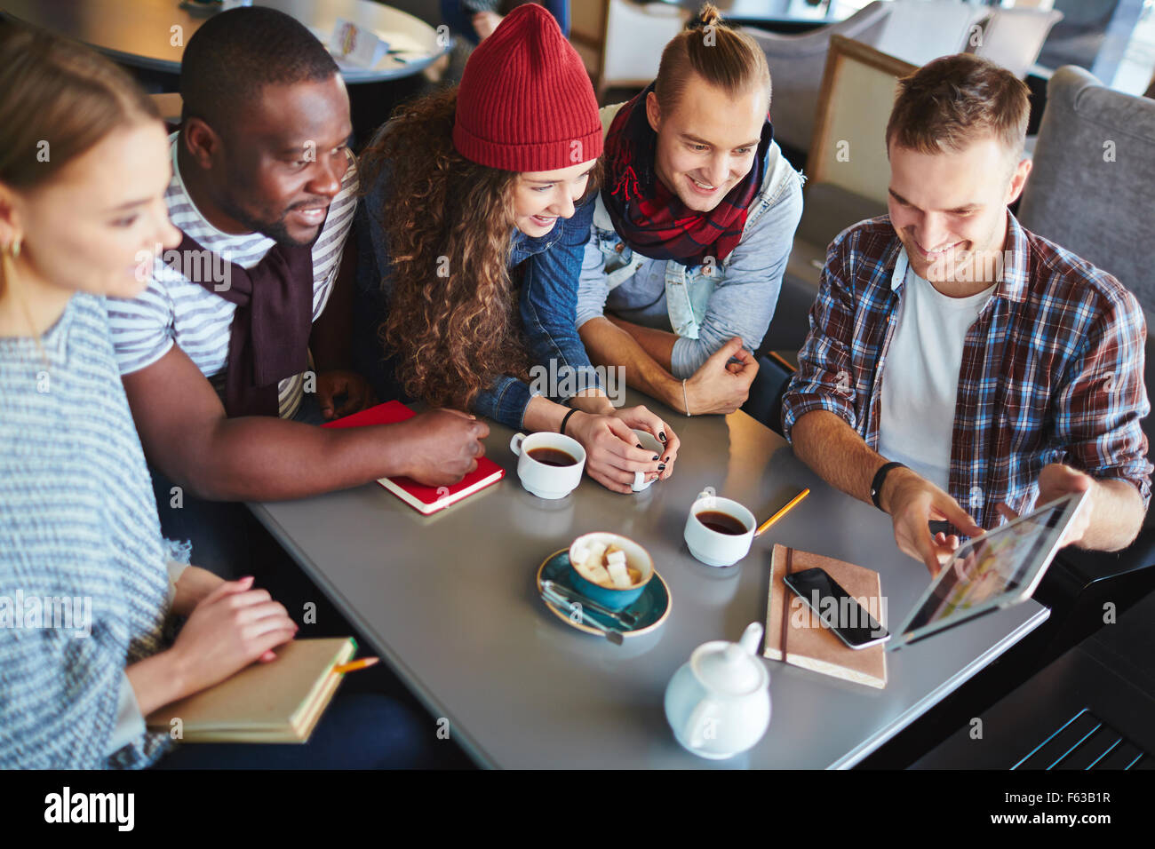 Group of friendly teens with touchpad networking in cafe Stock Photo ...