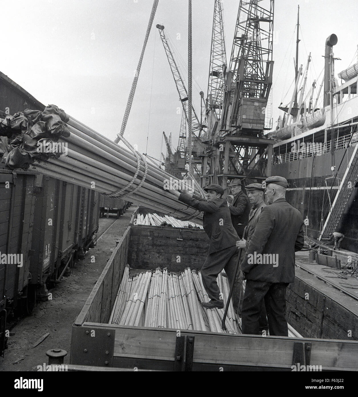 1950s historical picture, workers moving steel pipes from a lorry at ...