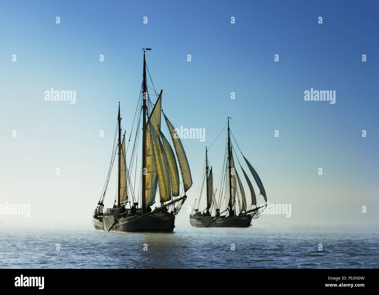 Back light image of two traditional sailing boats on the ocean ...