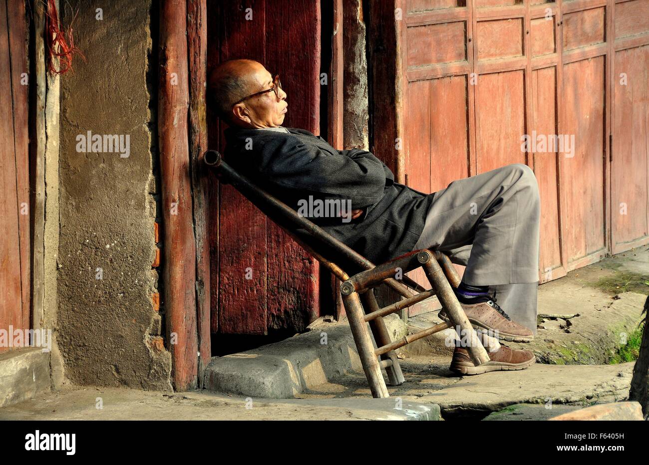 Jiu Chi Town, China: An elderly man sitting on a tilting bamboo chair ...