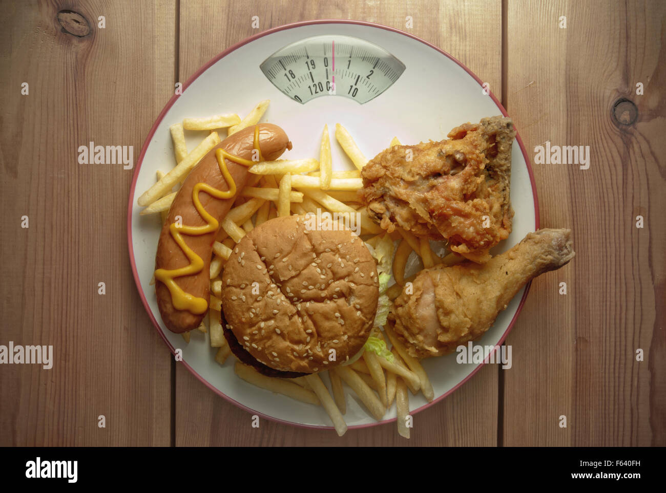 Plate packed with junk food with weighing scales Stock Photo - Alamy