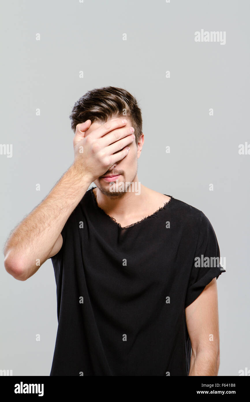 Young handsome man doing facepalm covering his eyes and face with palm ...
