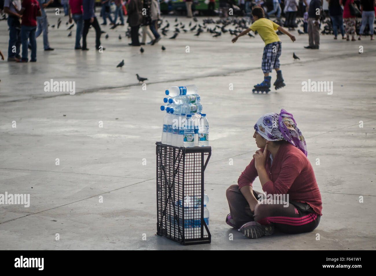 Woman selling bottled water in crowded public square while children ...