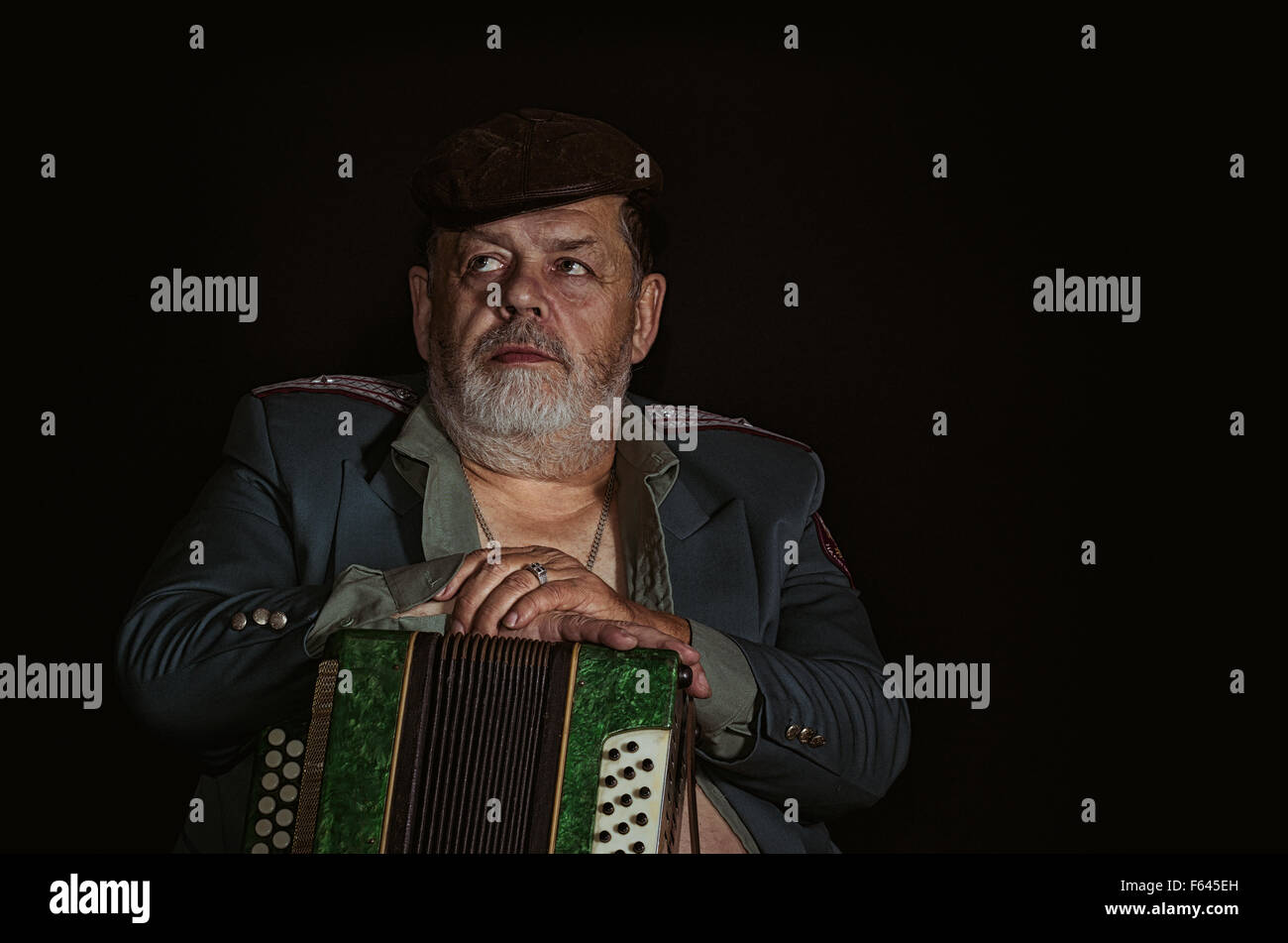 Portrait (low key) of an old retired military man with accordion ...