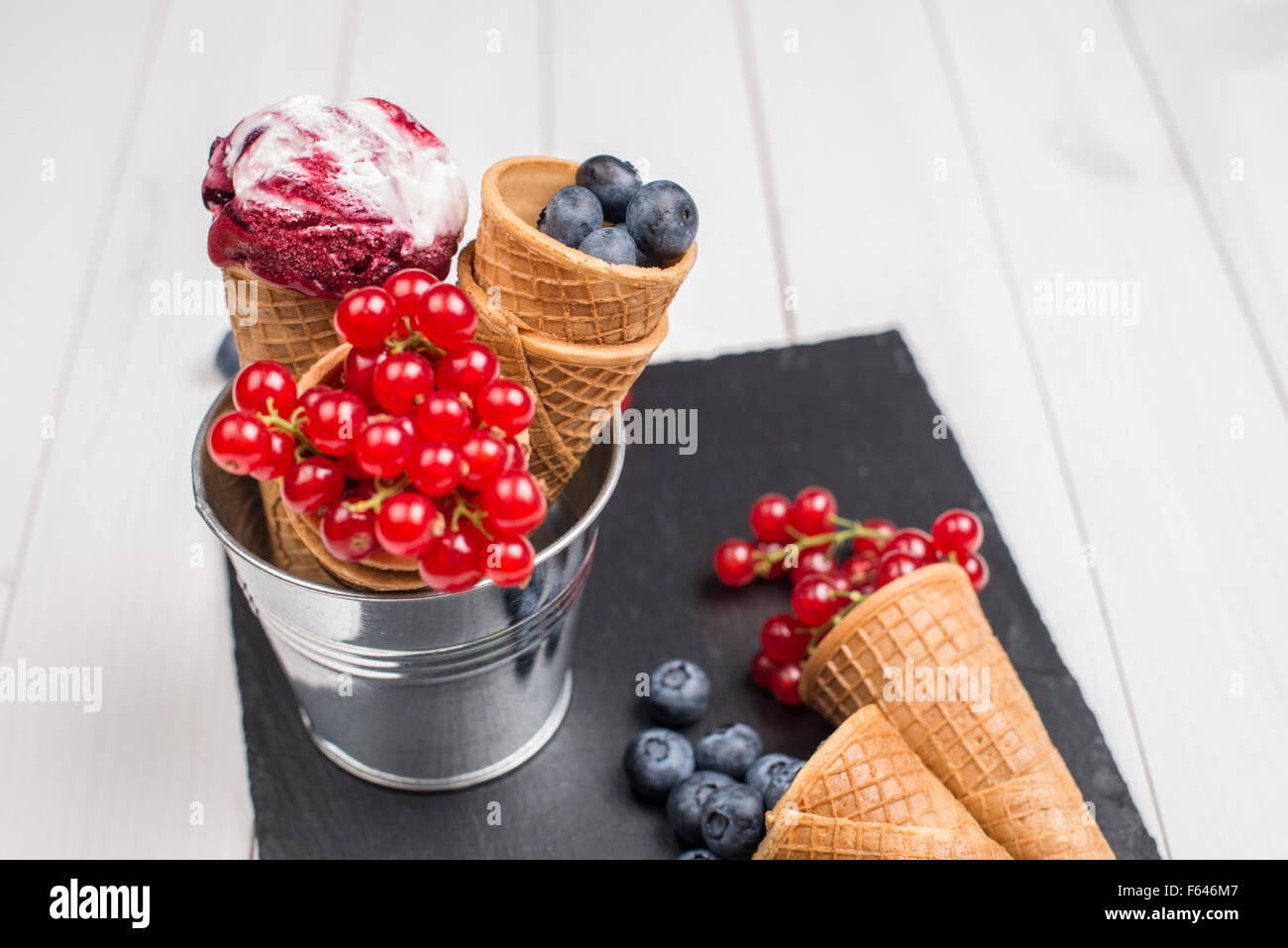 Red fruits ice cream cone on black slate board Stock Photo - Alamy