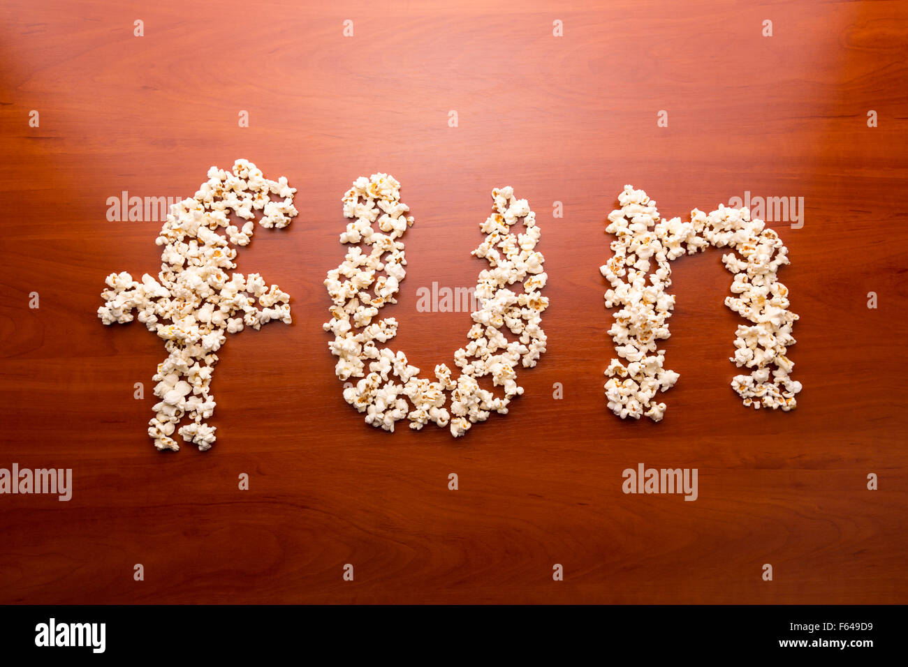 Popcorn forming the word "fun" on the wooden table Stock Photo - Alamy