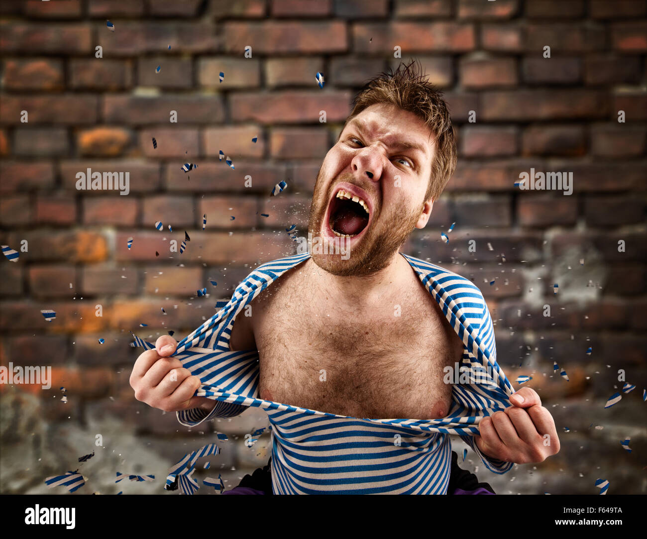 Angry man is tearing clothing on himself outdoors Stock Photo - Alamy