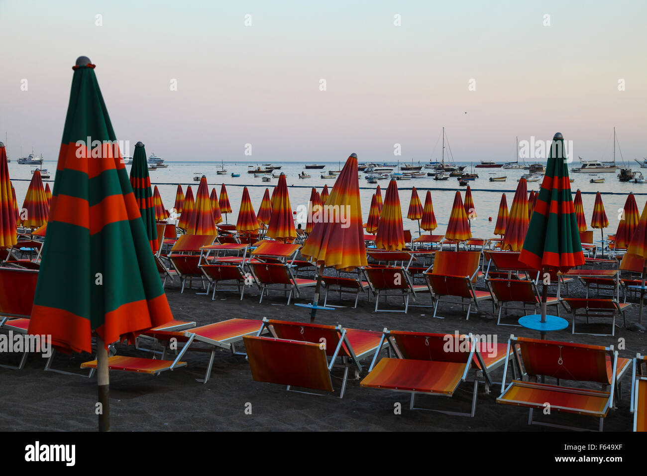 beach brollies folded down for the night, sun set red glow in the sky ...