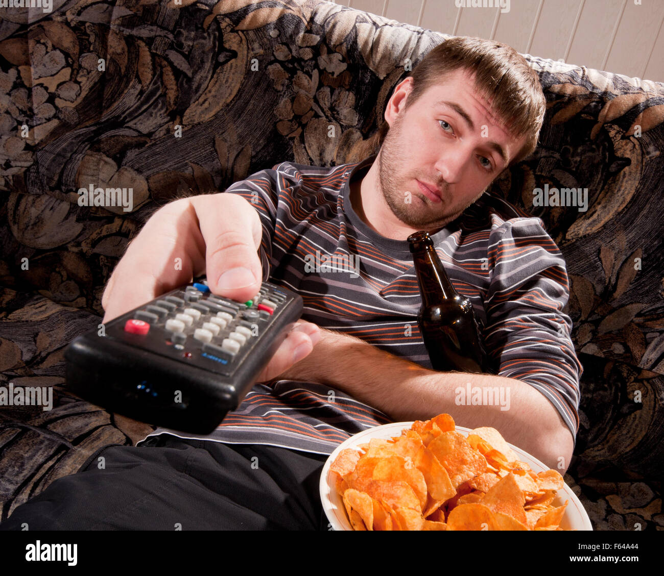 Sleepy man with beer and chips watching TV at home Stock Photo - Alamy
