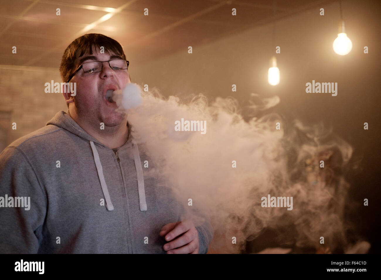 man blows billowing clouds of vapour while vaping using an electronic ...