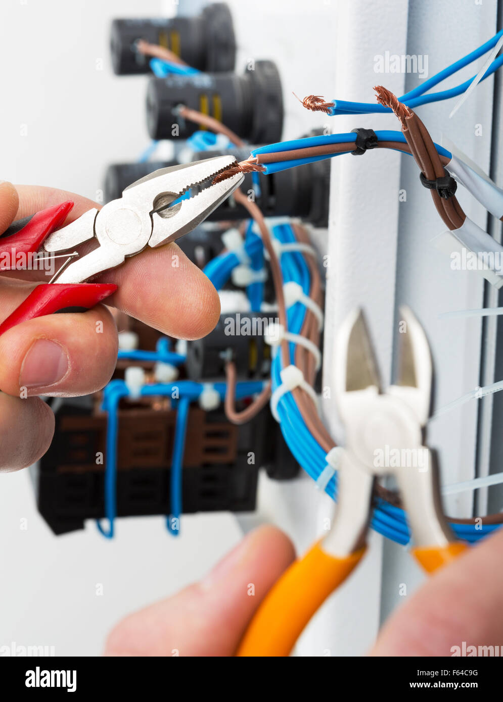 Hand of an electrician with tools at an electrical switchgear cabinet ...