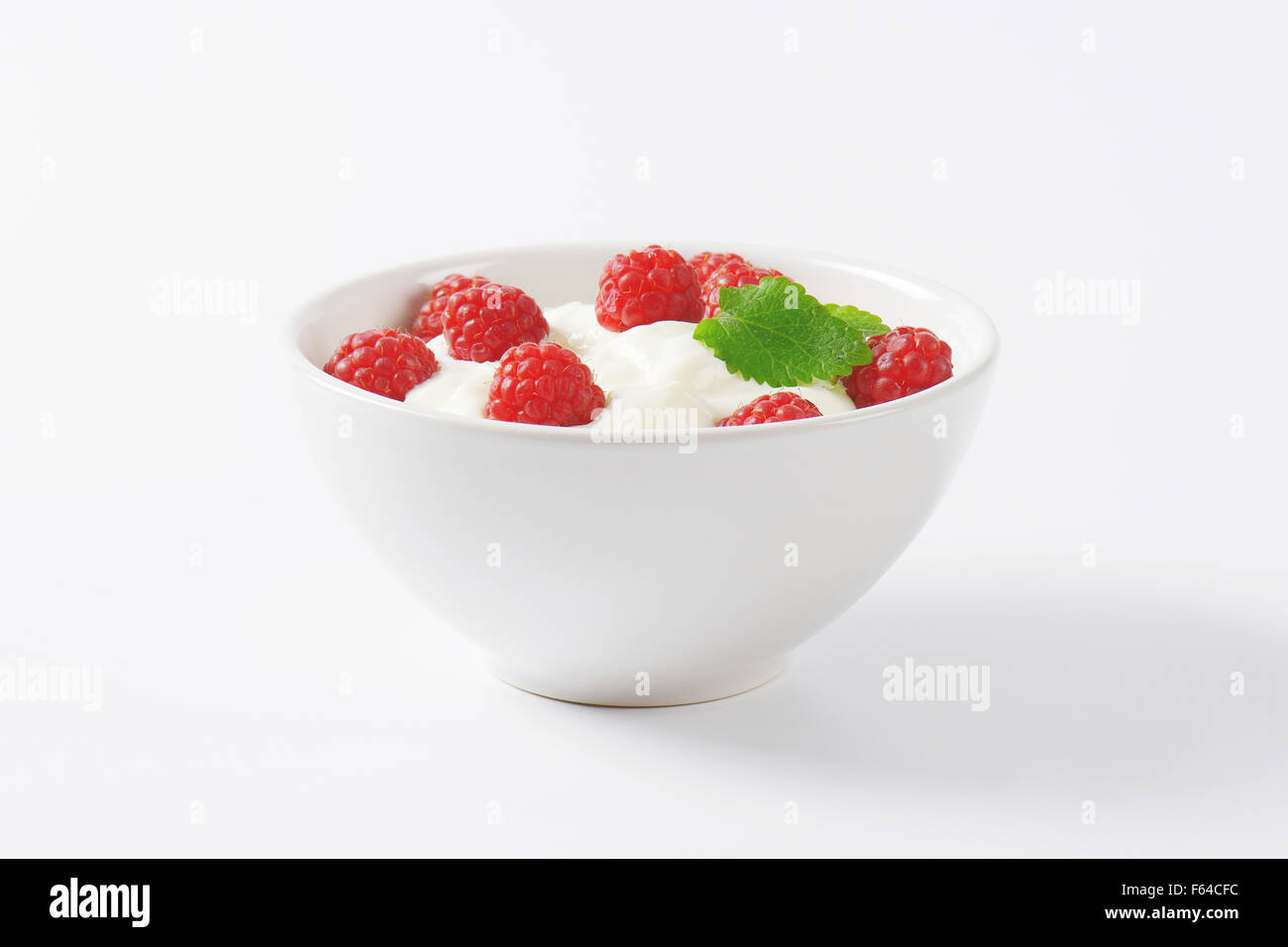 bowl of raspberries in yogurt on white background Stock Photo - Alamy