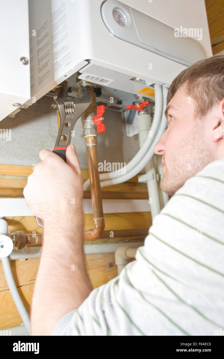 Plumber at work. Servicing gas boiler Stock Photo - Alamy