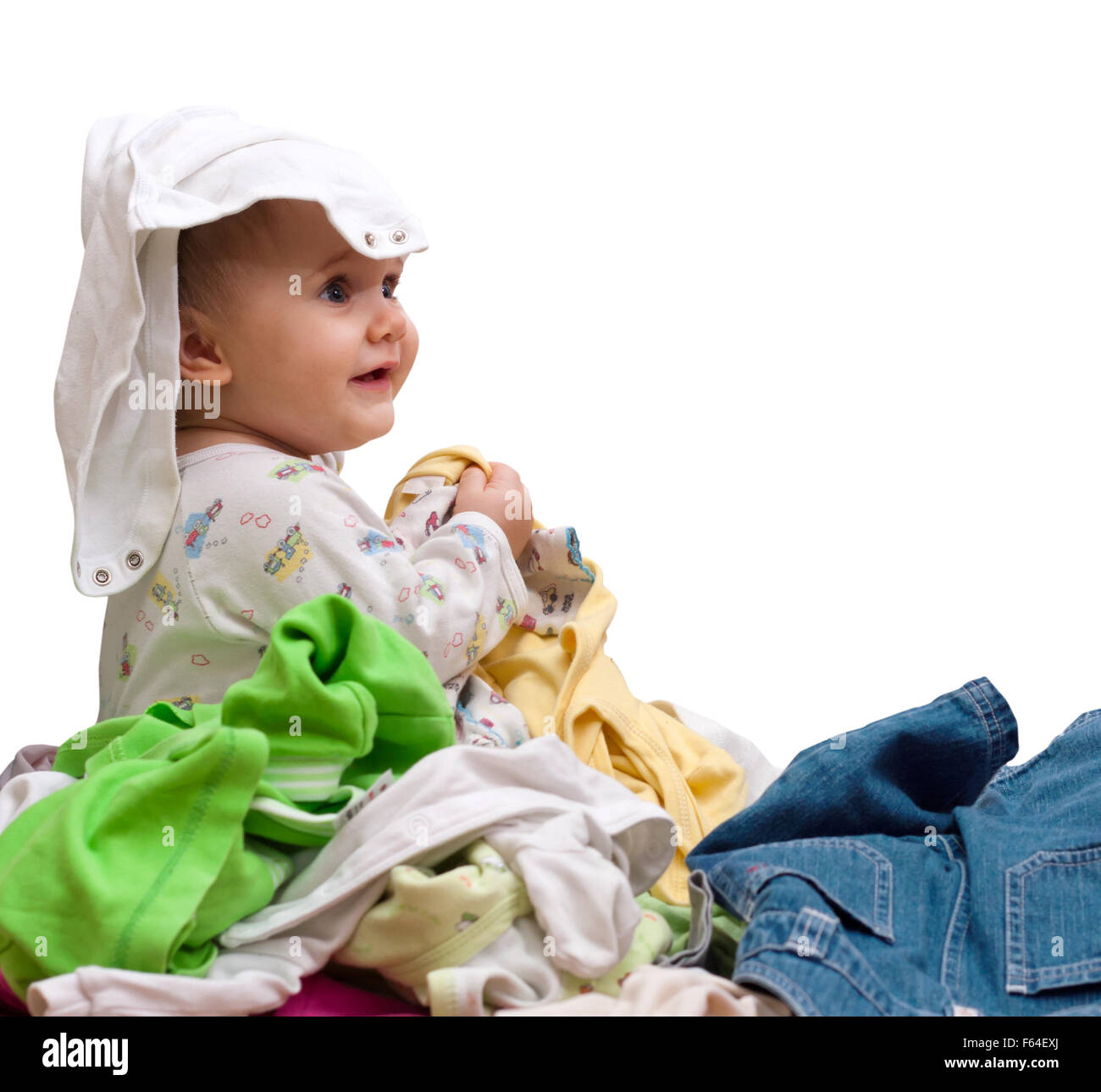 Happy baby girl playing in heap of baby's wear. Isolated Stock Photo ...