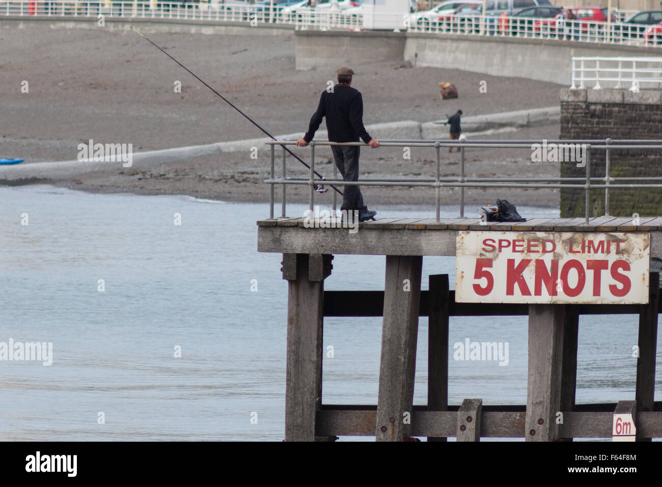 Man standing on the end of a jetty next to his fishing rod Stock Photo ...