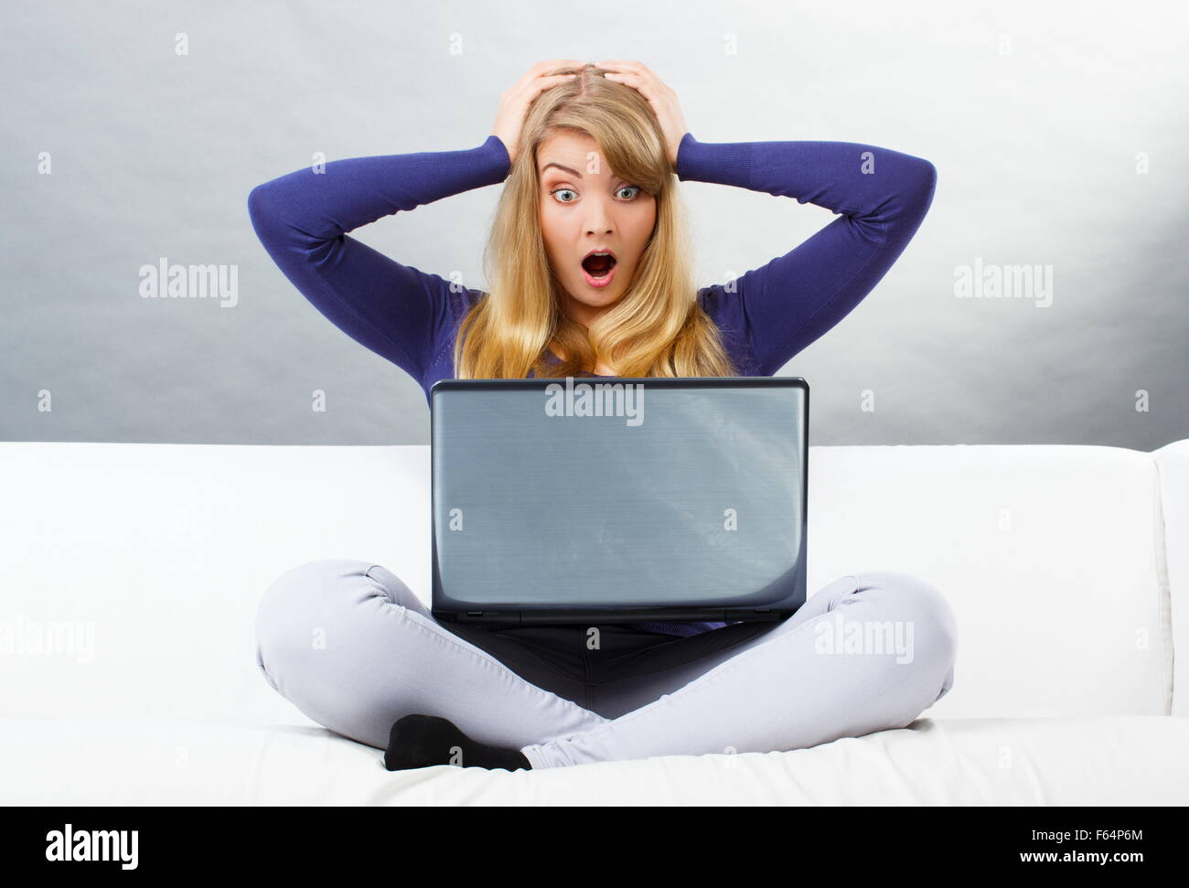 Shocked, surprised and scared woman holding hands on her head, sitting ...