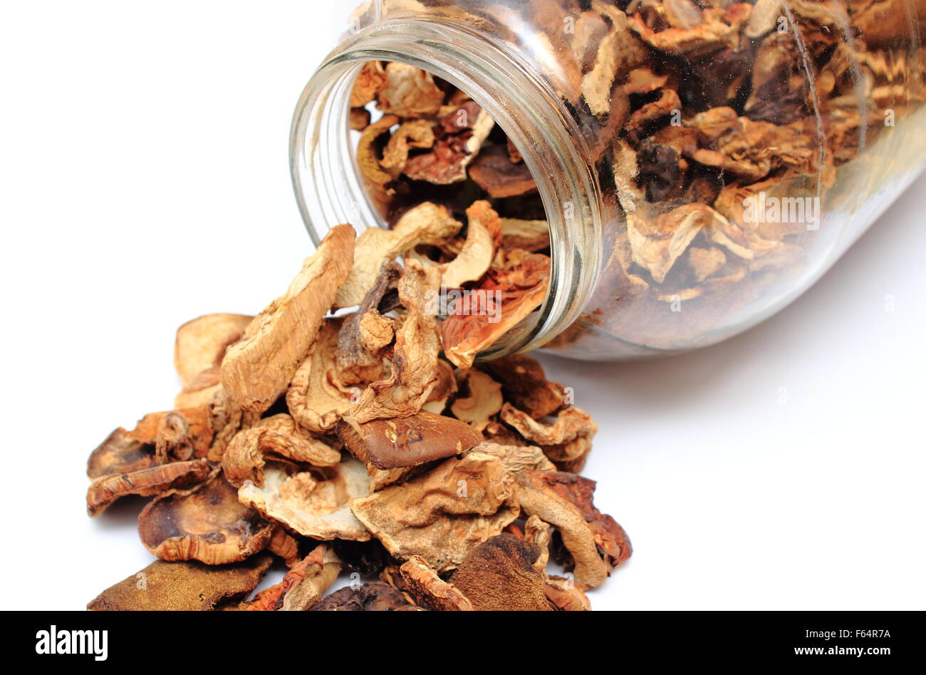 Dried forestry mushrooms pouring out of glass jar. Isolated on white ...