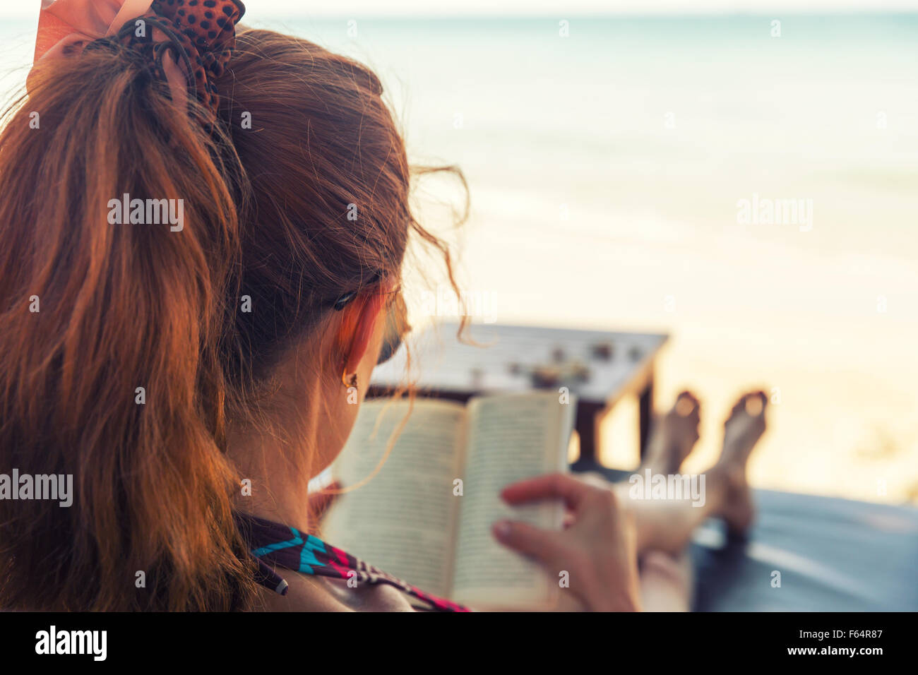 Young woman reading a book at the beach Stock Photo - Alamy