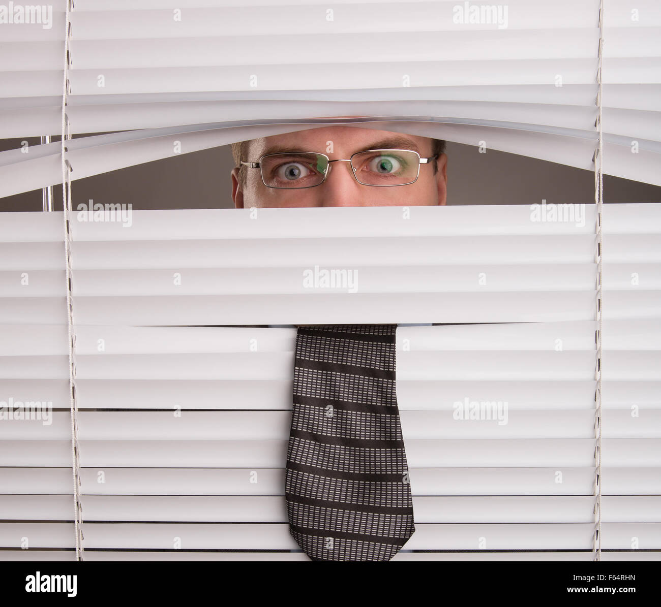 A young man looking through window blinds Stock Photo - Alamy