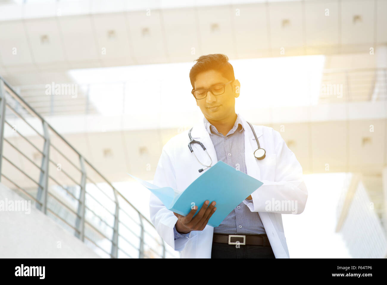 Portrait of Asian Indian medical doctor reading on medical report ...