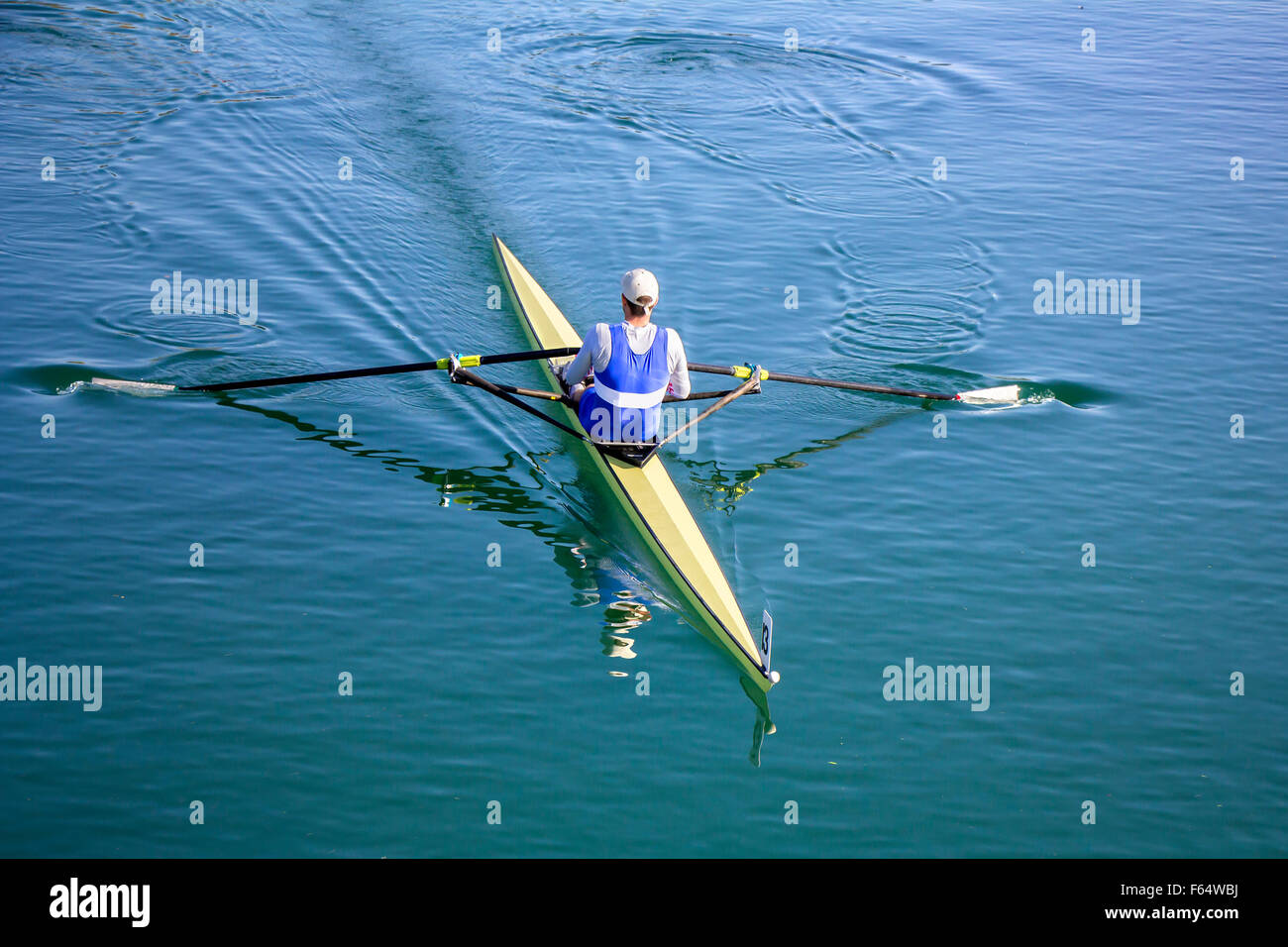 Young man Rower in a boat, rowing on the tranquil lake Stock Photo - Alamy