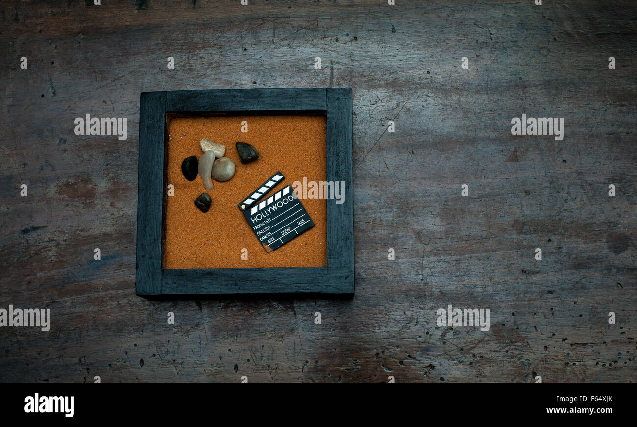 Zen garden with stones and movie clapper board, orange sand on aged ...