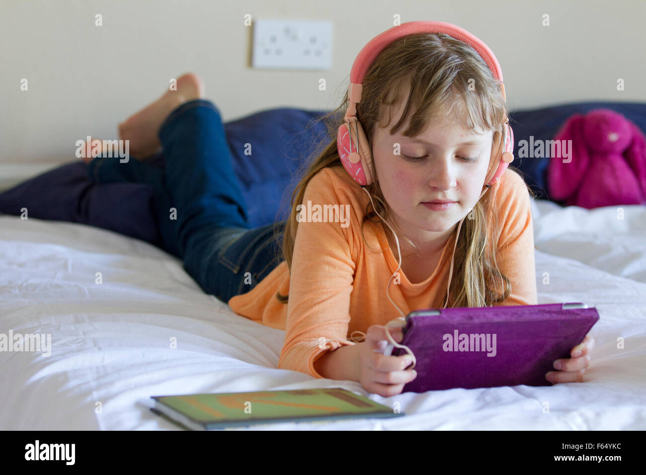 Girl working on iPad mini with headphones Stock Photo - Alamy