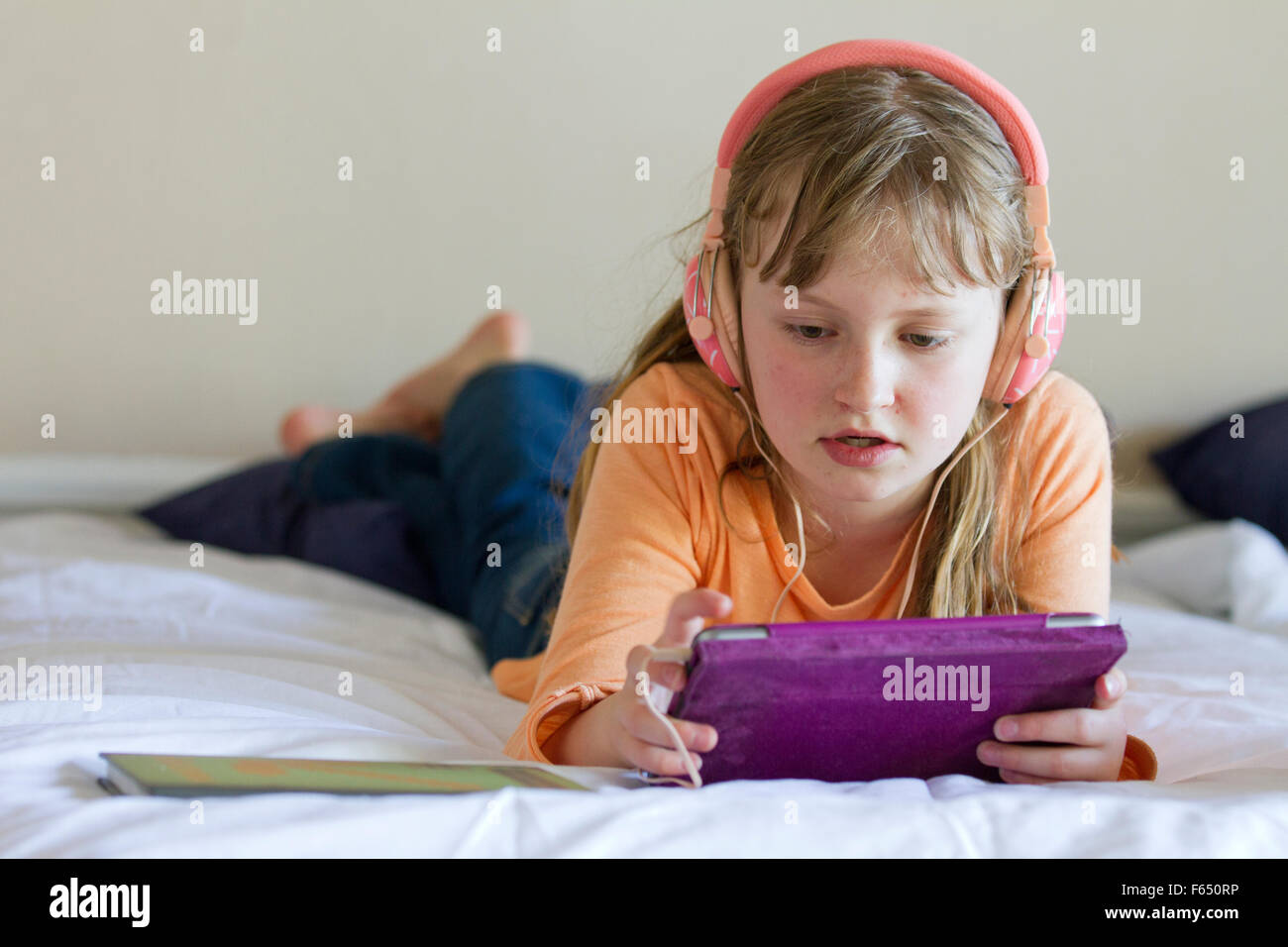 Girl working on iPad mini with headphones Stock Photo - Alamy