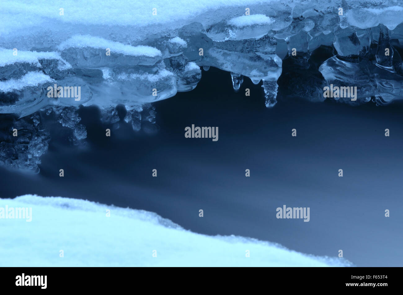 hole in river ice in winter and beautiful frozen ice shapes and water ...