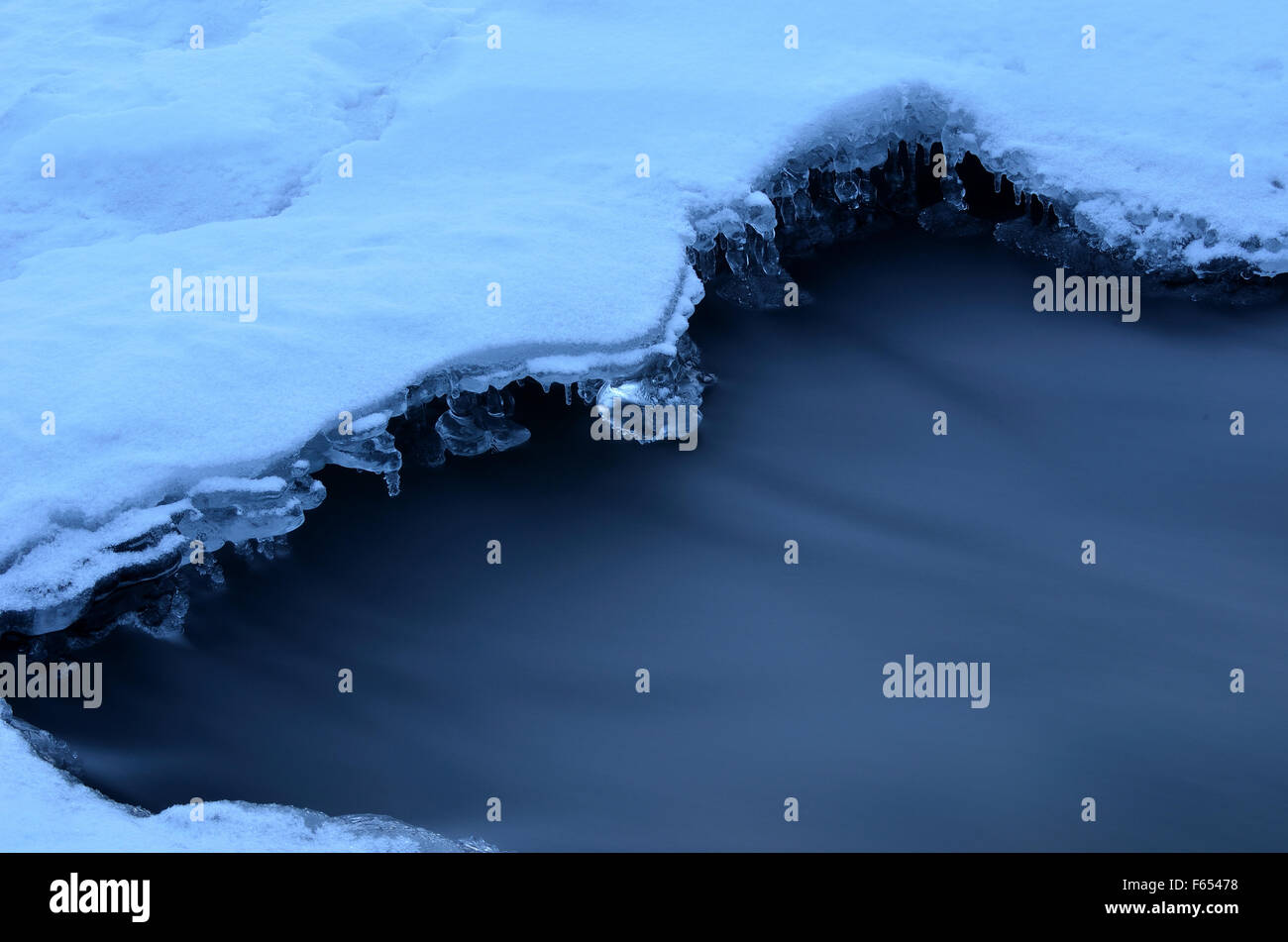 hole in river ice in winter and beautiful frozen ice shapes and water ...