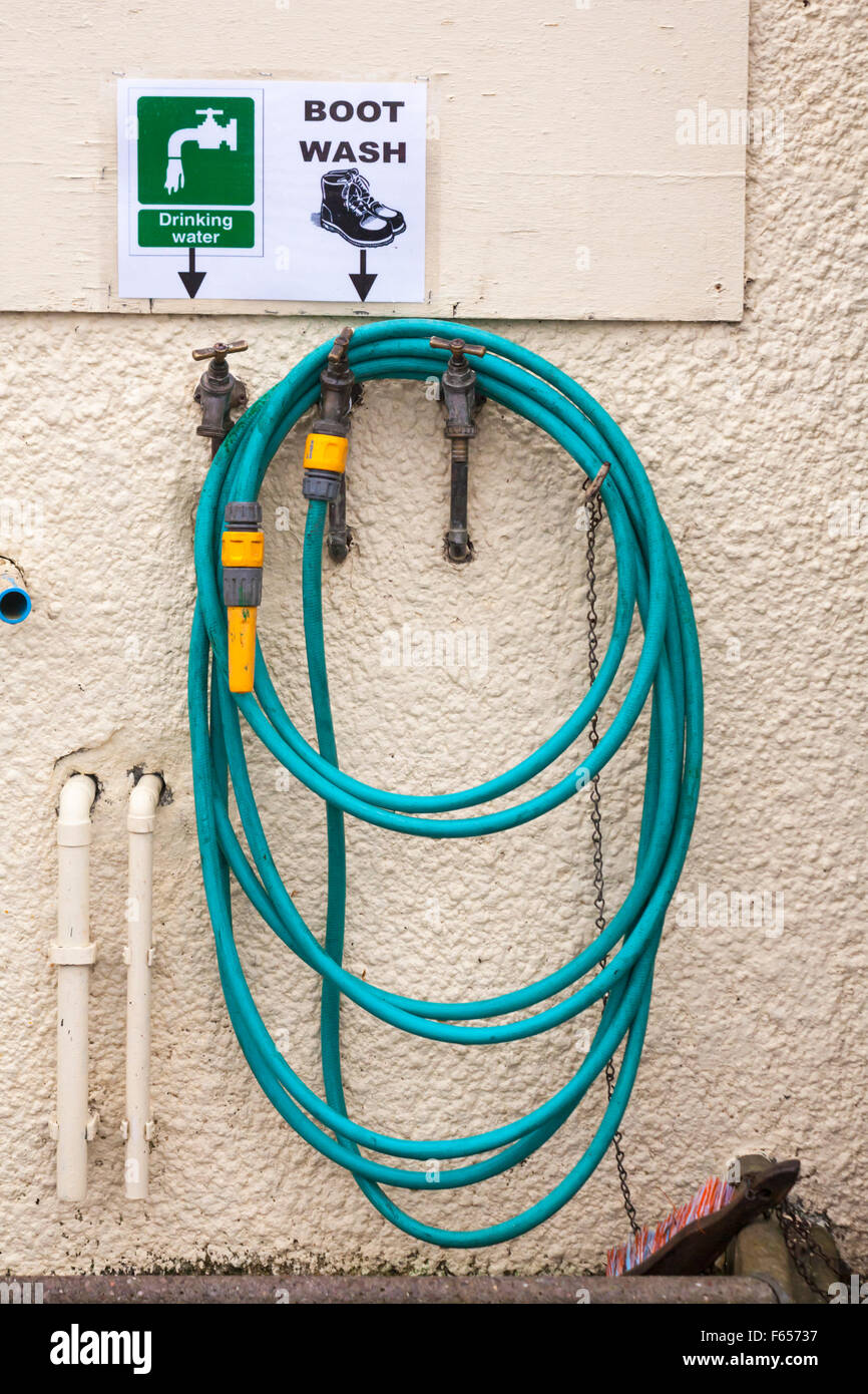 Boot wash tap with hose and drinking water tap and signs in farm ...