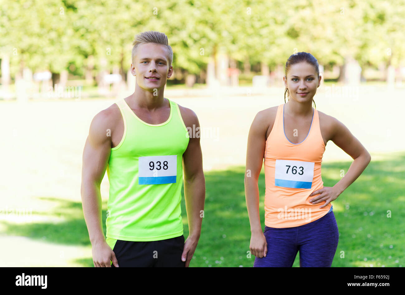 happy friends or couple with racing badge numbers Stock Photo - Alamy