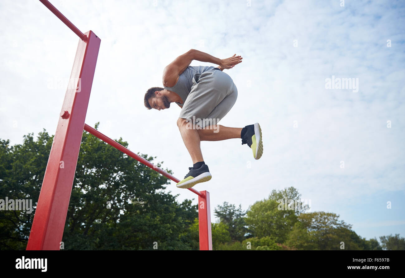 young man jumping on horizontal bar outdoors Stock Photo - Alamy