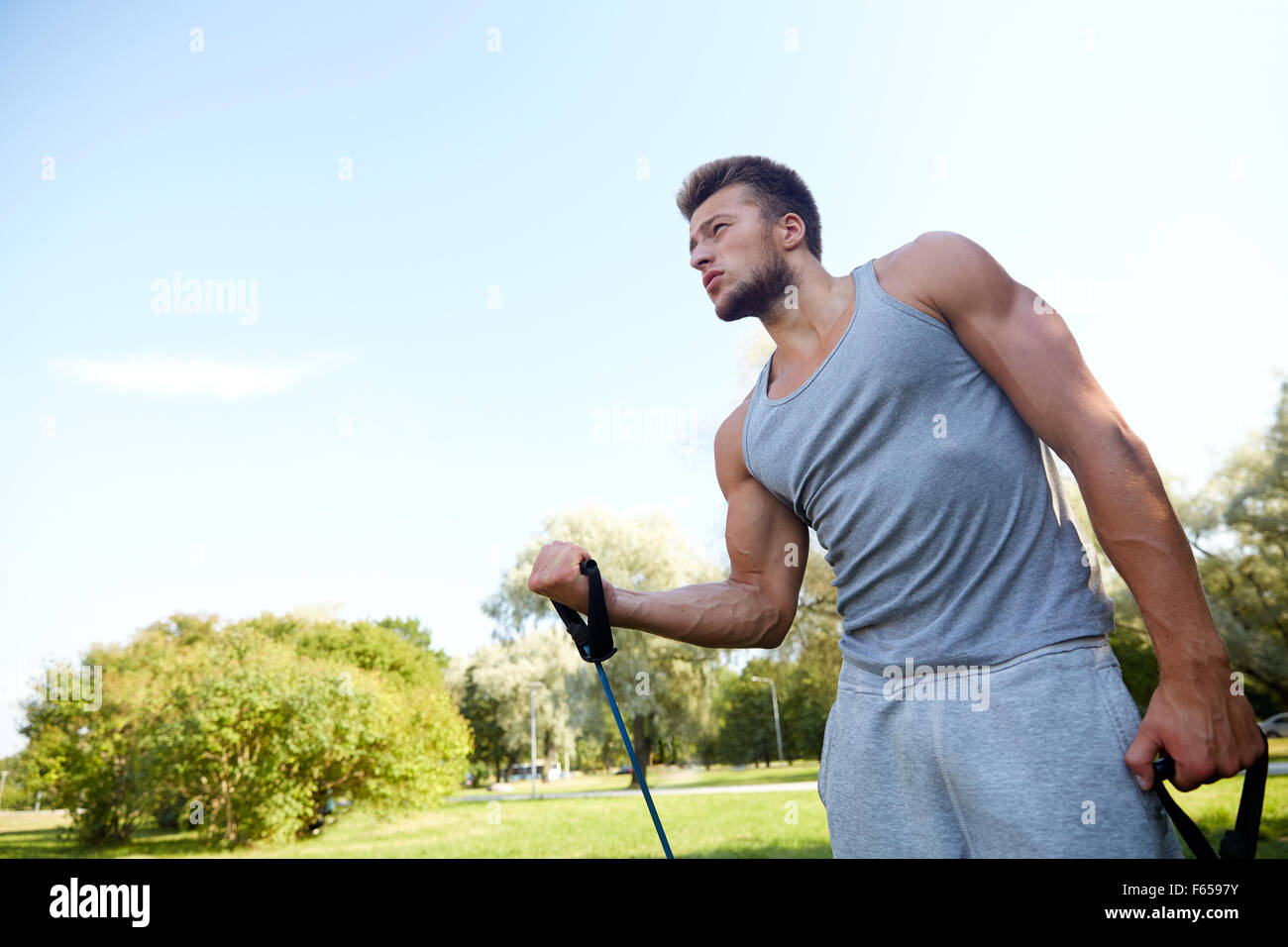 young man exercising with expander in summer park Stock Photo - Alamy